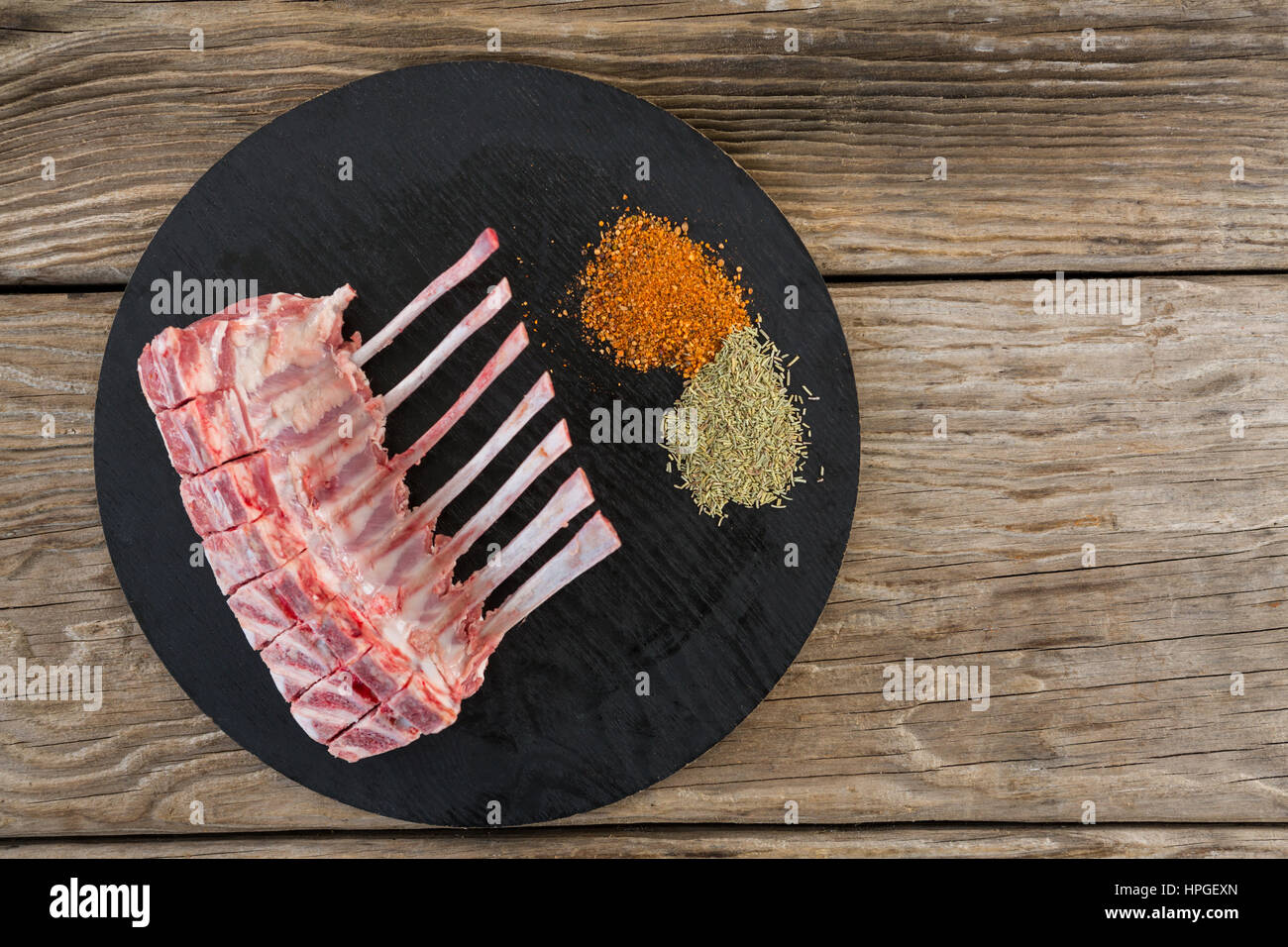 Raw beef ribs rack and spices on black round tray against wooden ...