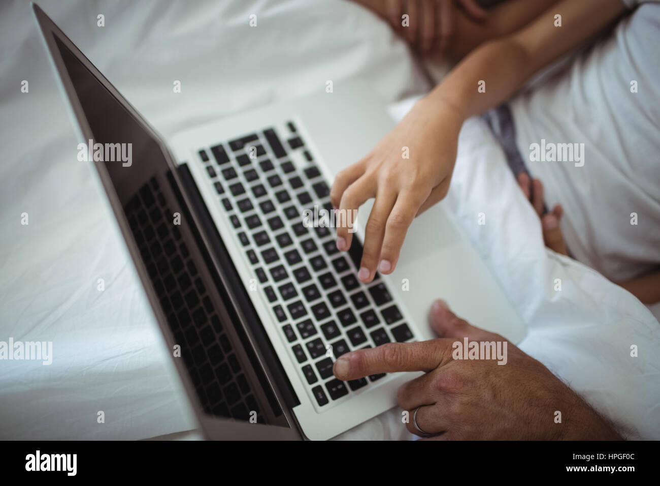 Parents and kids using laptop in bed at home Stock Photo - Alamy