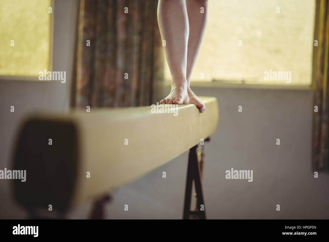 Low-section of female gymnast practicing gymnastics on the balance beam ...