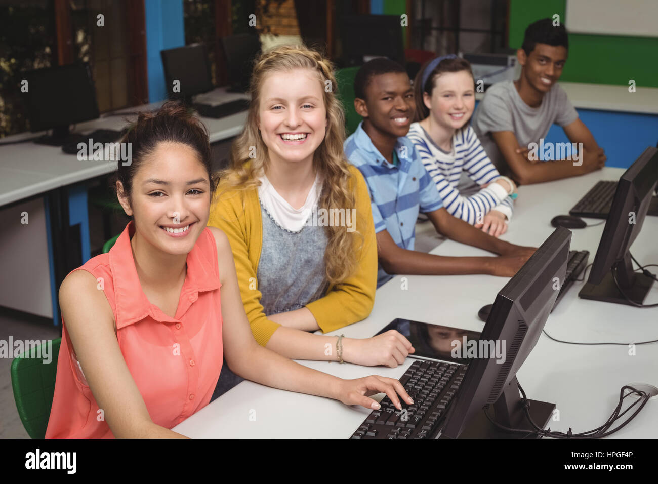 Portrait of smiling students studying in computer classroom at school ...