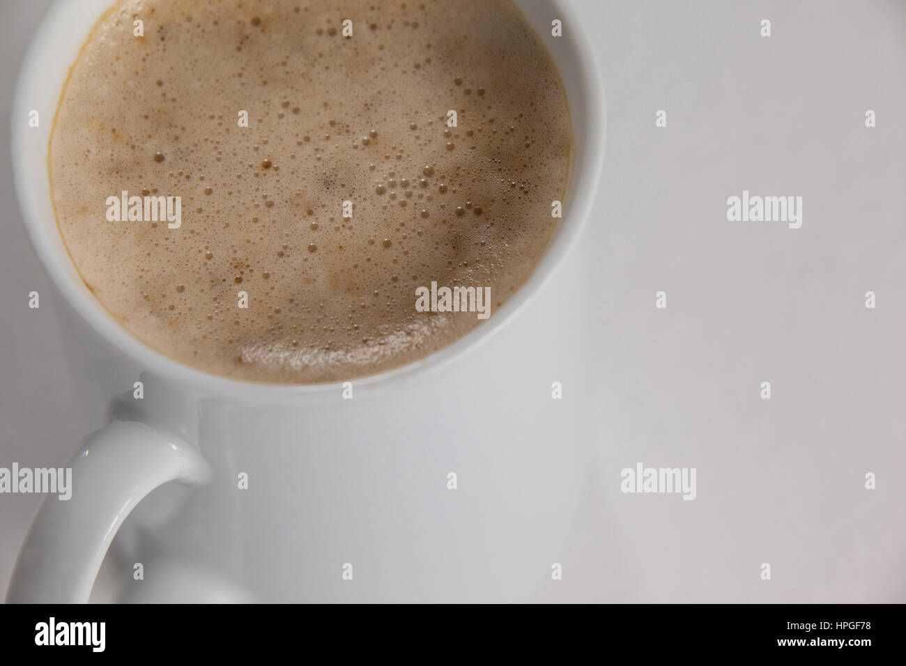 Close-up of white mug of coffee with creamy froth on white background ...