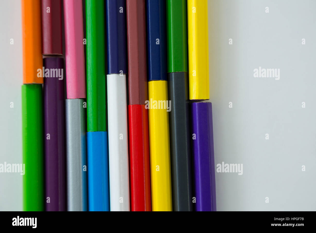 Close-up of colored pencils arranged in interlock pattern on white ...