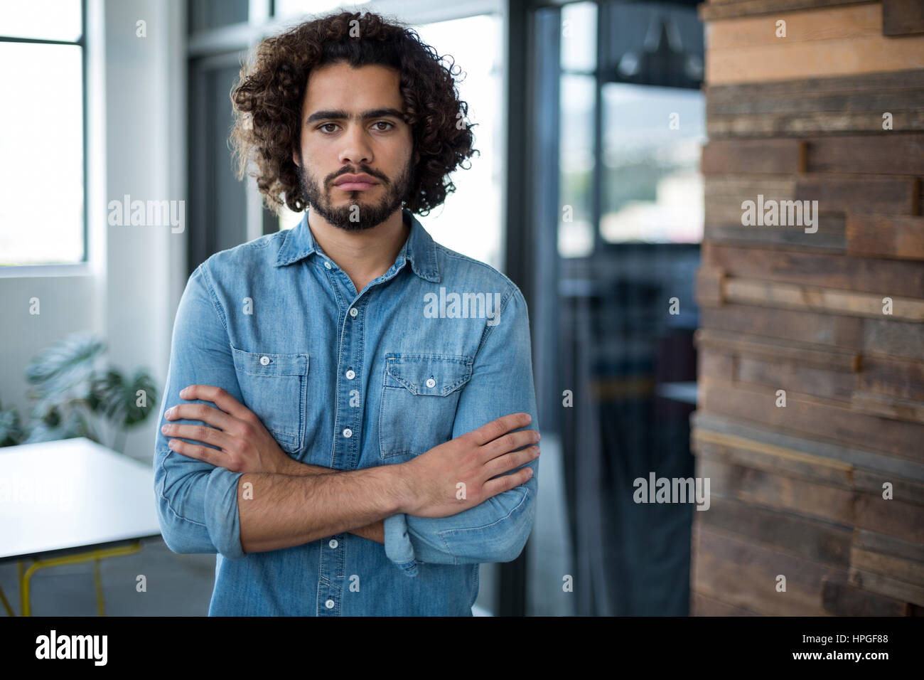 Portrait of sad business executive standing with arms crossed in office ...