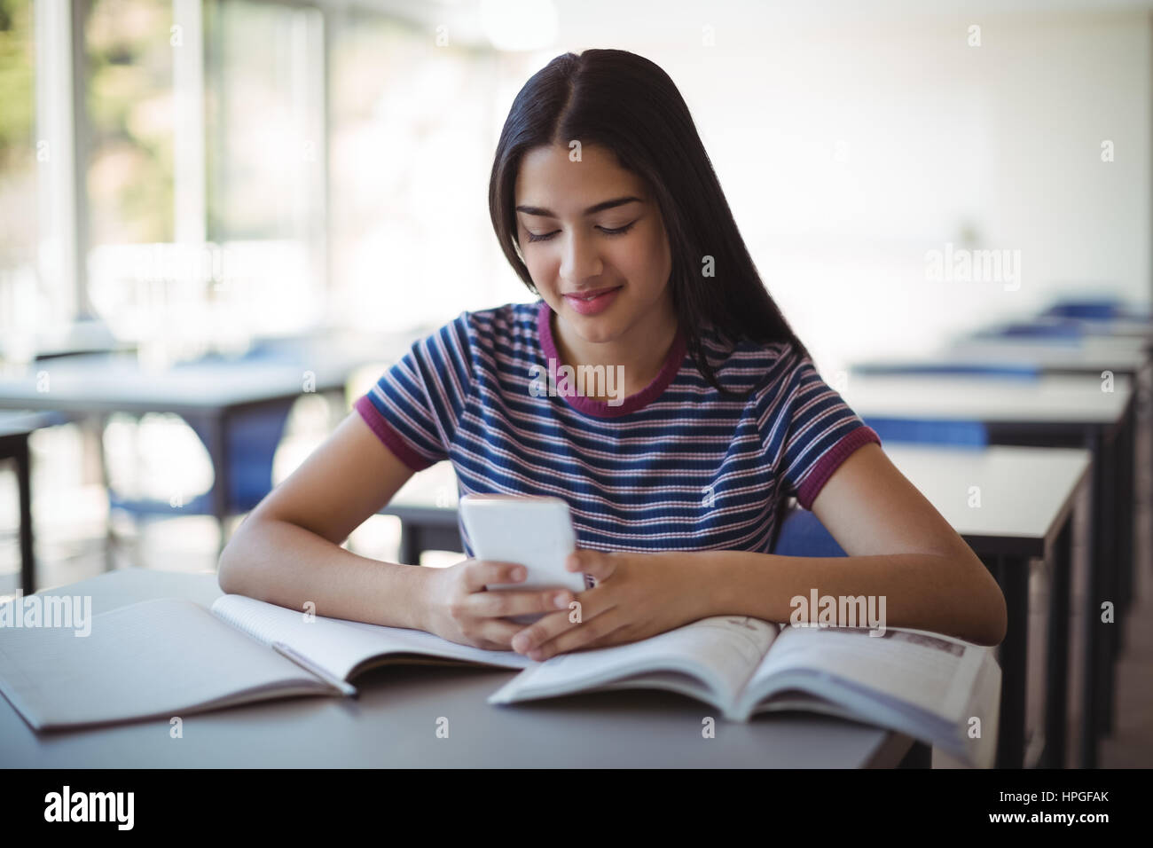 Schoolgirl using mobile phone while studying in classroom at school ... Schoolgirl using mobile phone while studying in classroom at school ...