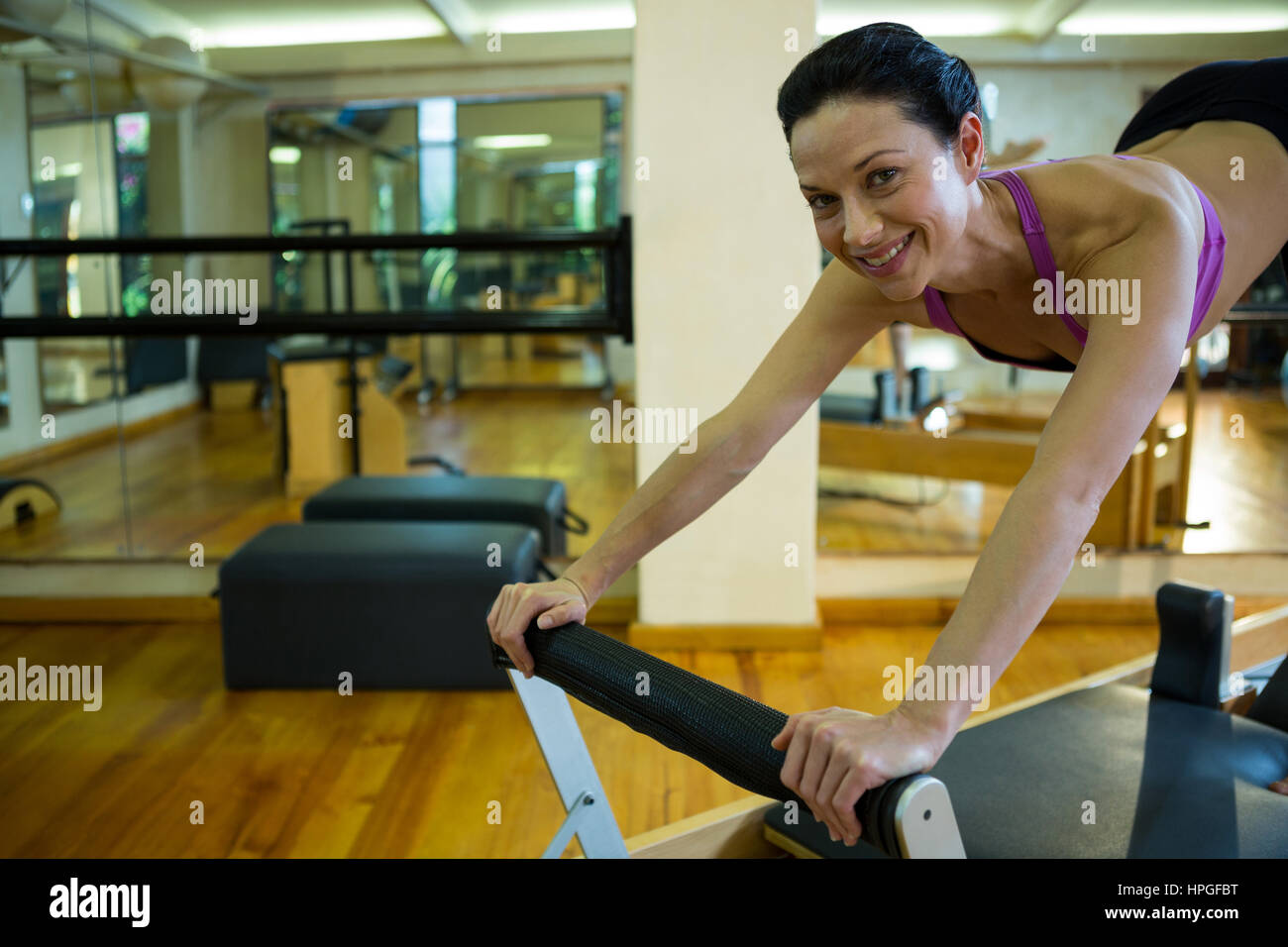 Portrait of happy woman practicing stretching exercise in gym Stock ...