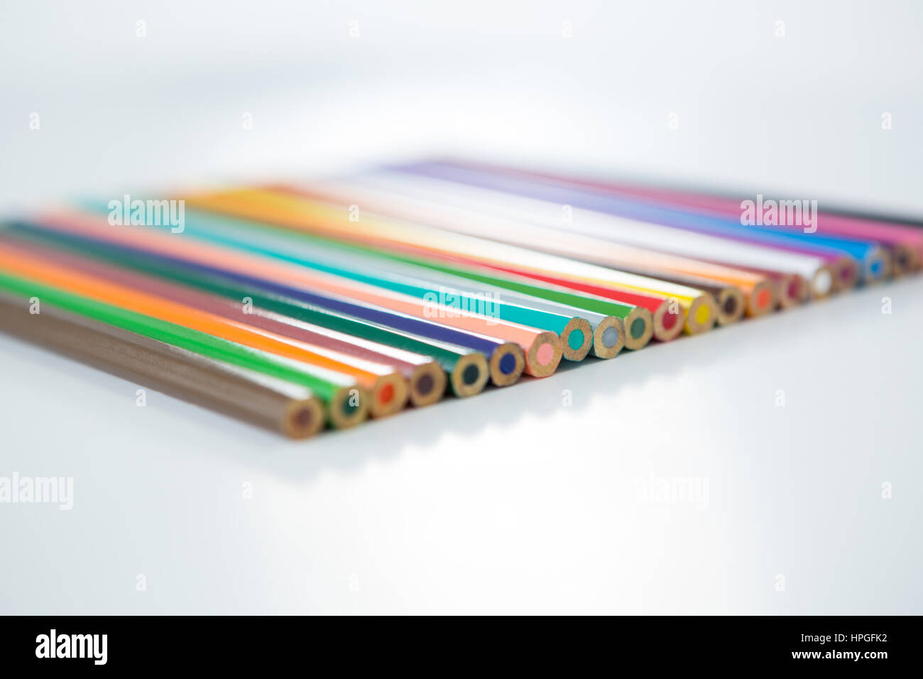 Colored pencils arranged in a row on white background Stock Photo - Alamy