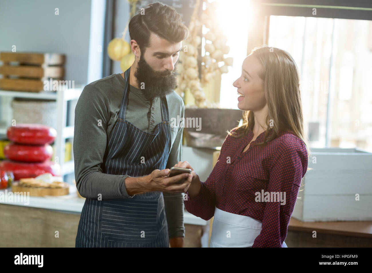 Smiling bakery staff using mobile phone at counter in bake shop Stock ...