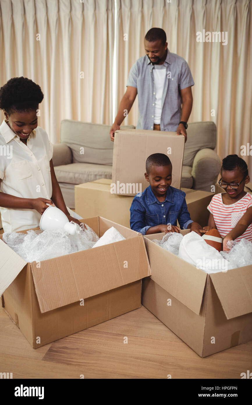 Parents and kids opening cardboard boxes in living room at home Stock ...