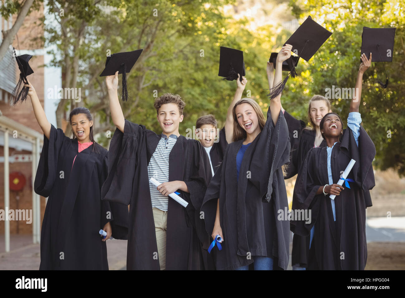 Portrait of graduate school kids standing with degree scroll and ...