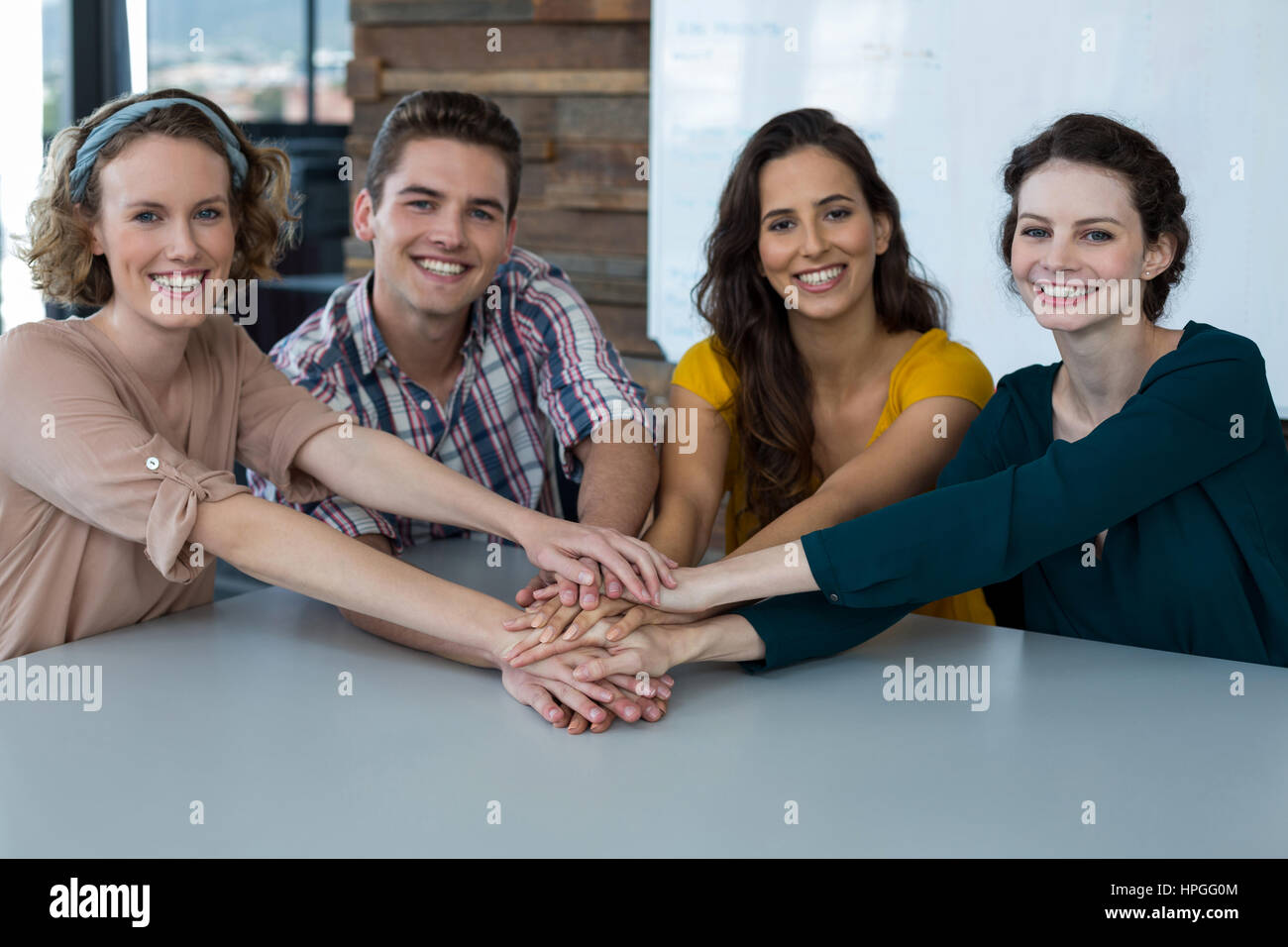 Portrait of smiling business executives forming hand stack in office ...