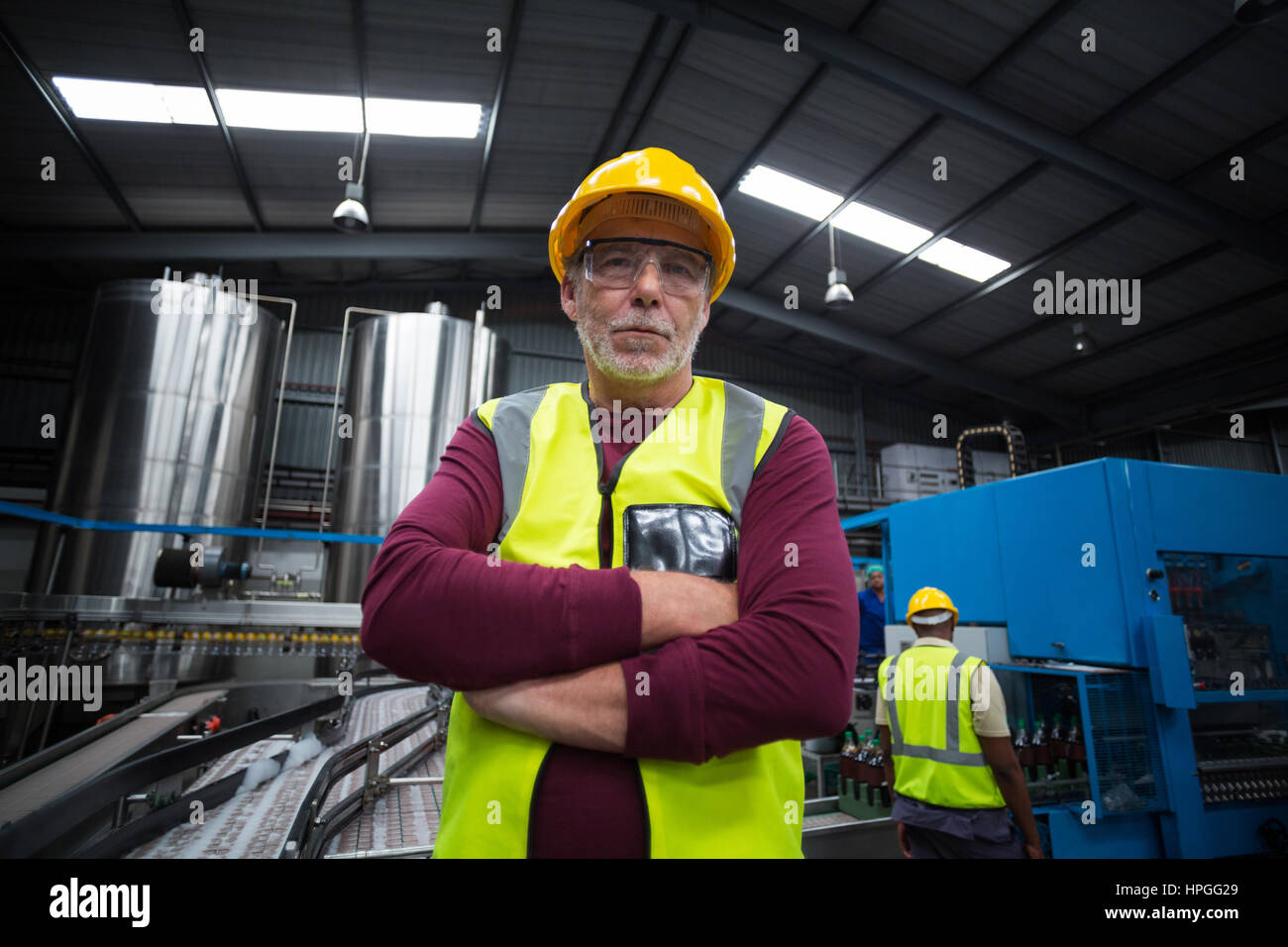 Portrait of confident factory worker standing with her arms crossed ...
