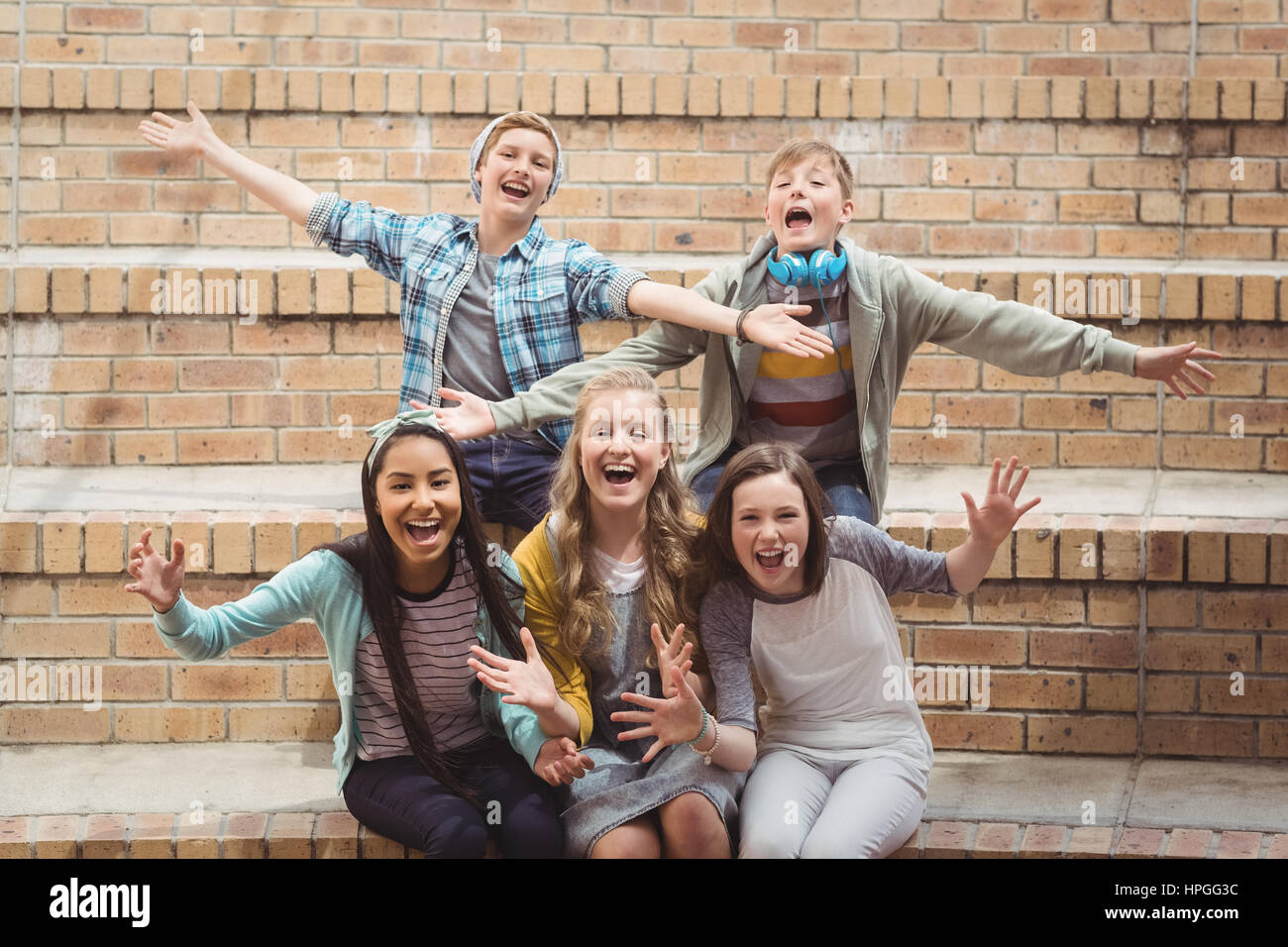 Portrait of smiling school students sitting on staircase having fun in ...
