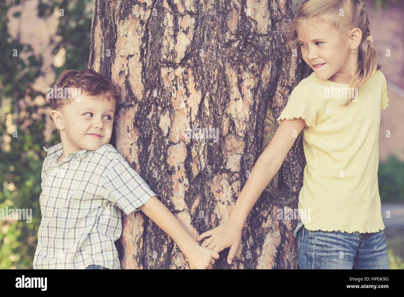 Two happy children playing near the tree at the day time Stock Photo ...