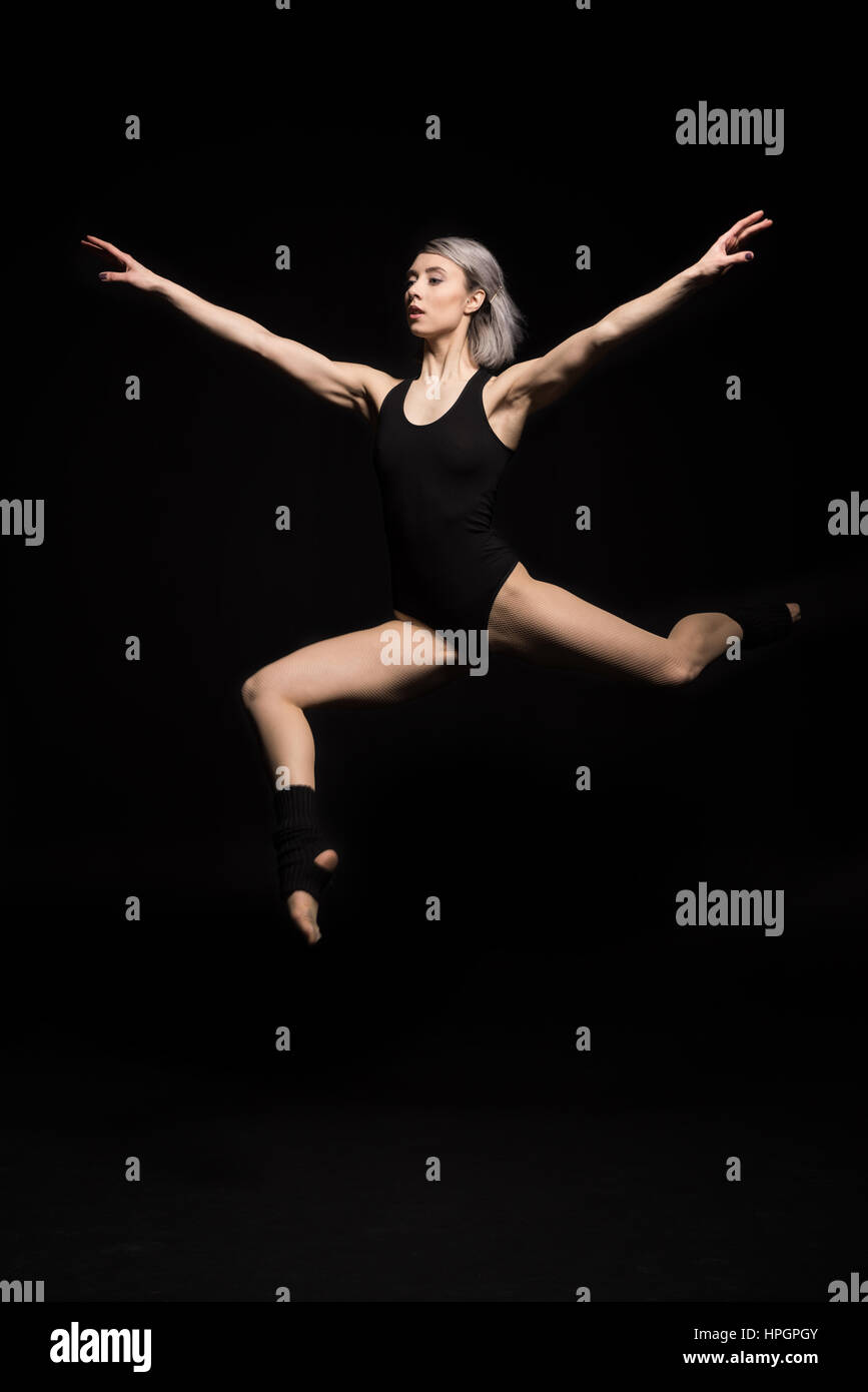 side view of focused jumping woman in bodysuit Stock Photo - Alamy