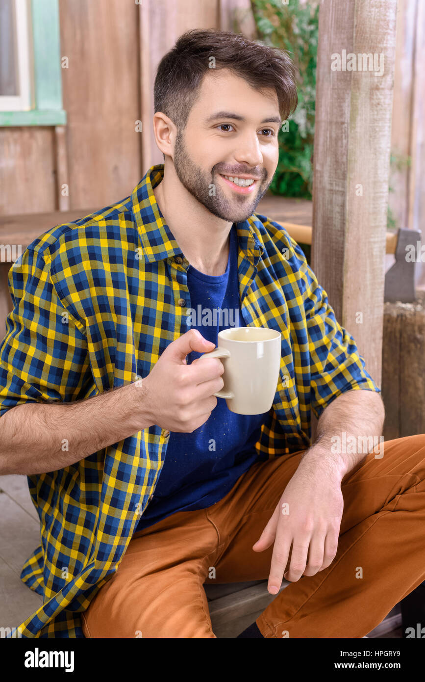 man sitting on porch with cup of tea and looking away Stock Photo - Alamy