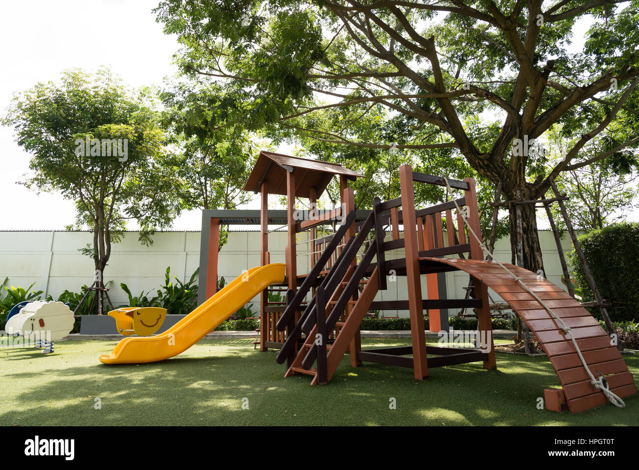 Set of children playground under big tree in the park Stock Photo - Alamy