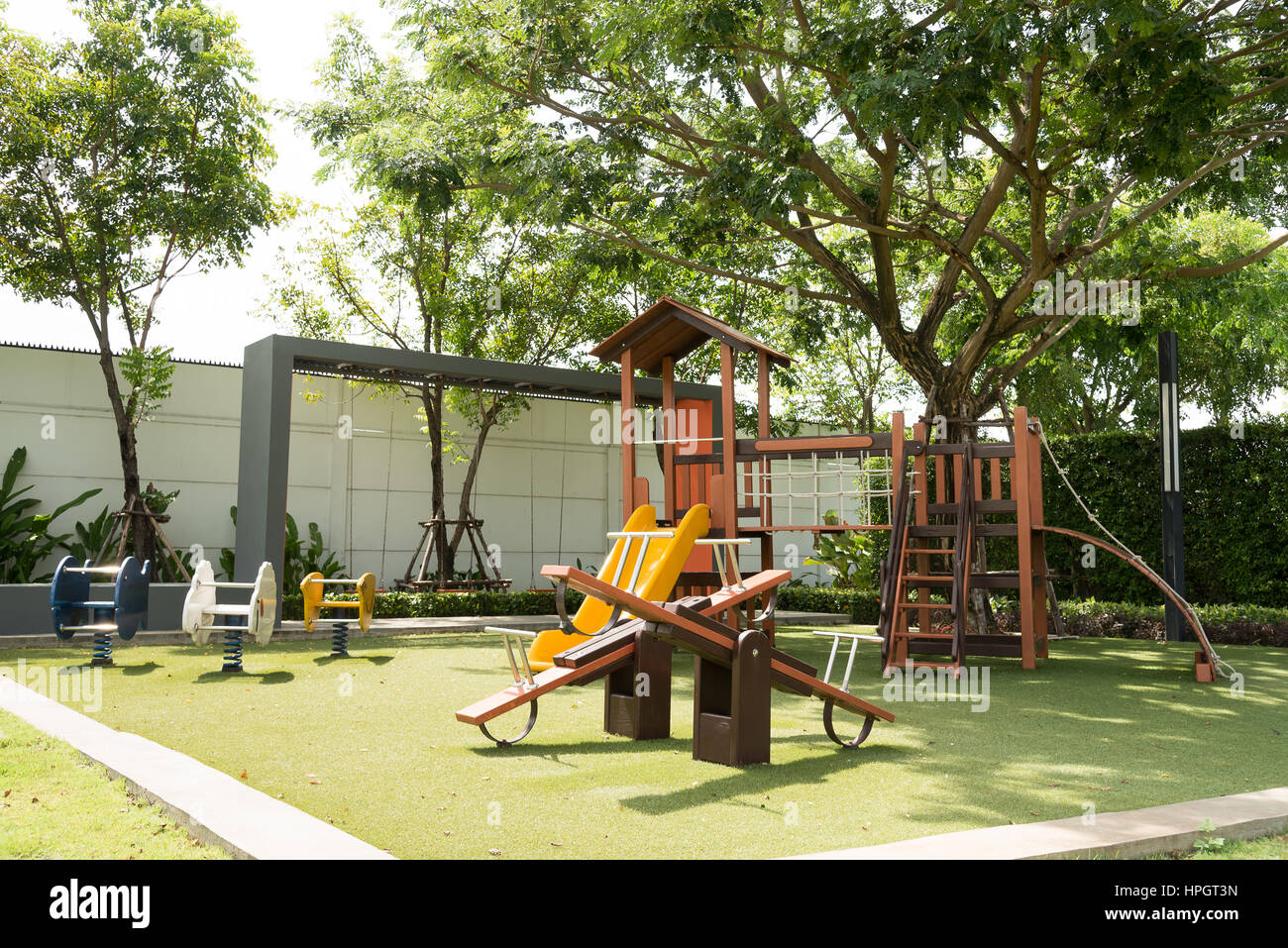 Set of children playground under big tree in the park Stock Photo - Alamy