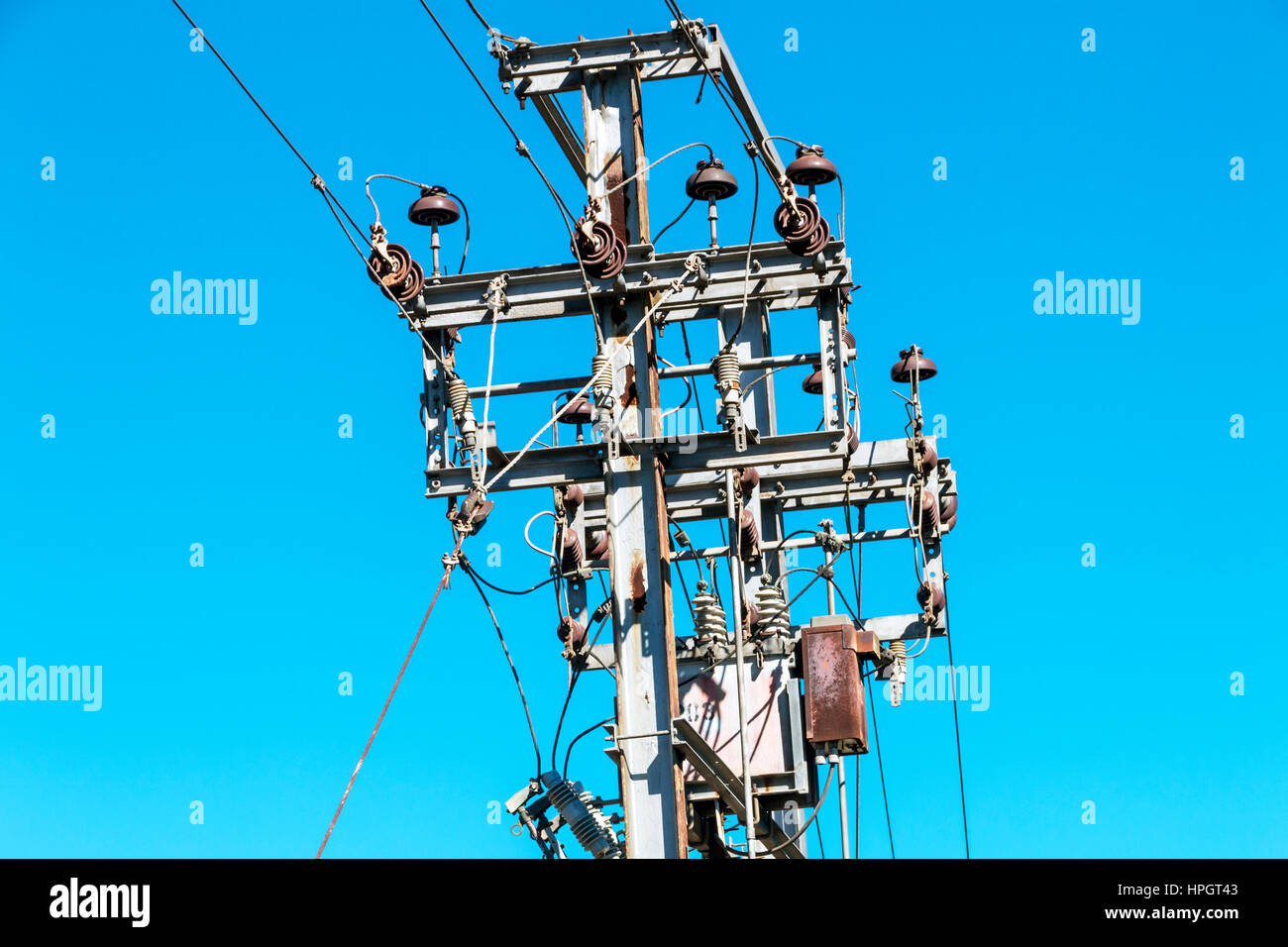 Overhead electric grid power line junction on steel pole against blue ...