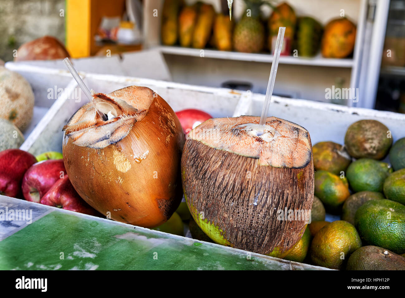 Green coconuts with drinking straws on fruit stand. Coconut water ...