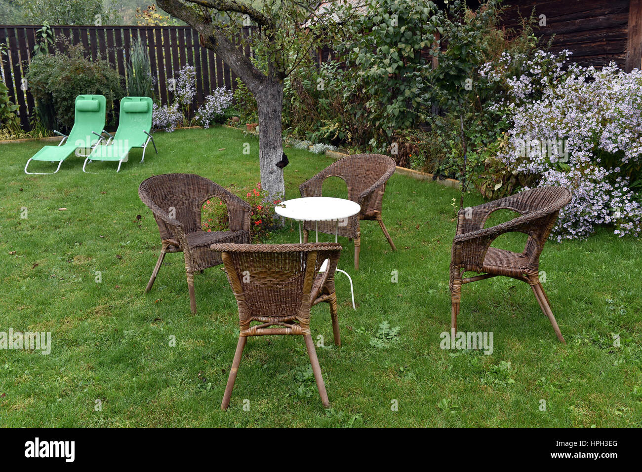 Rattan chairs and white table in a garden. Smoking area Stock Photo - Alamy