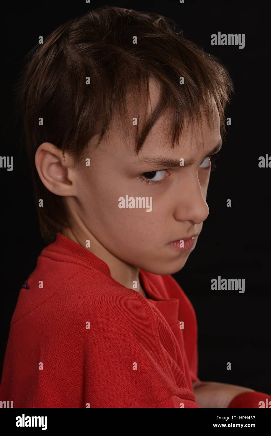 resentful young guy in the red shirt on a black background Stock Photo ...