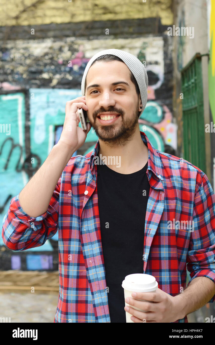Handsome young latin man talking on the phone. Trendy and urban scene ...