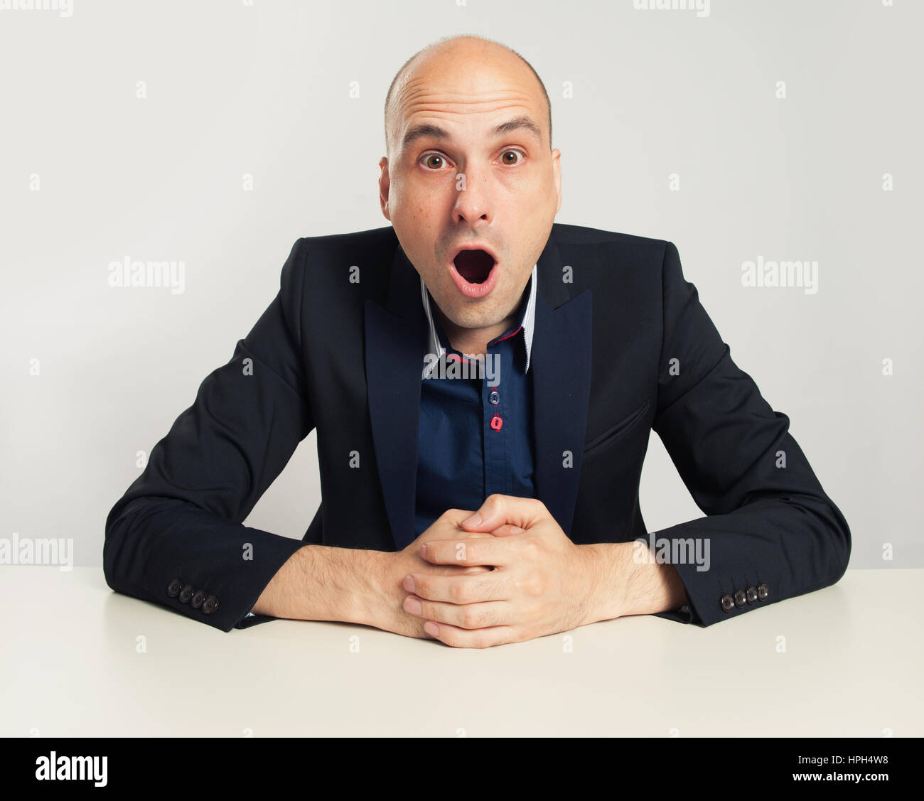 Shocked bald businessman sitting at the desk Stock Photo - Alamy