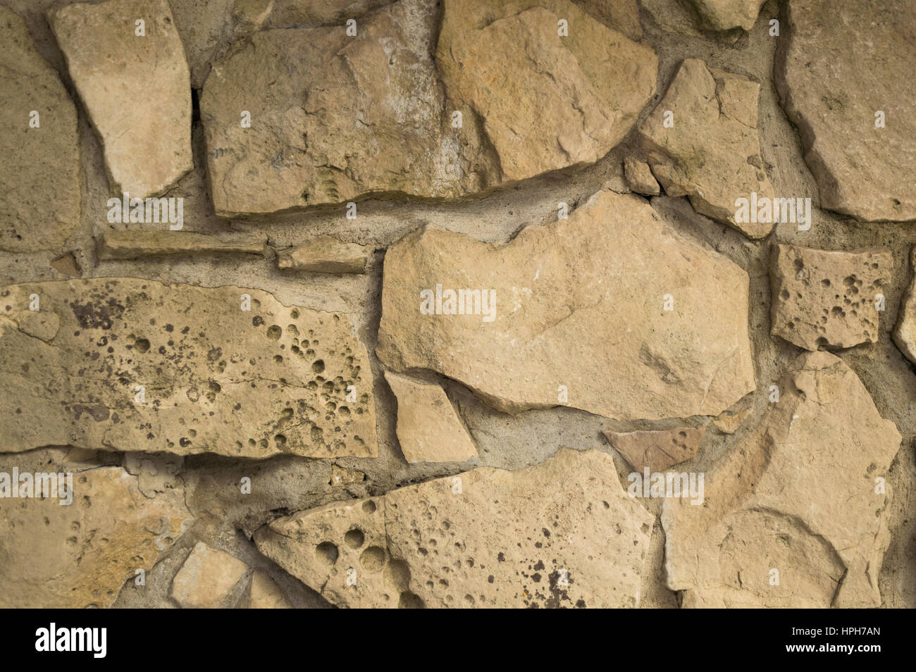 Rugged old limestone wall that is uneven, rustic and filled with cement ...