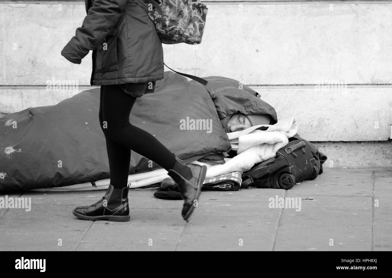 Homeless Man Sleeping Rough On Streets Of Brighton As Passer By Walks