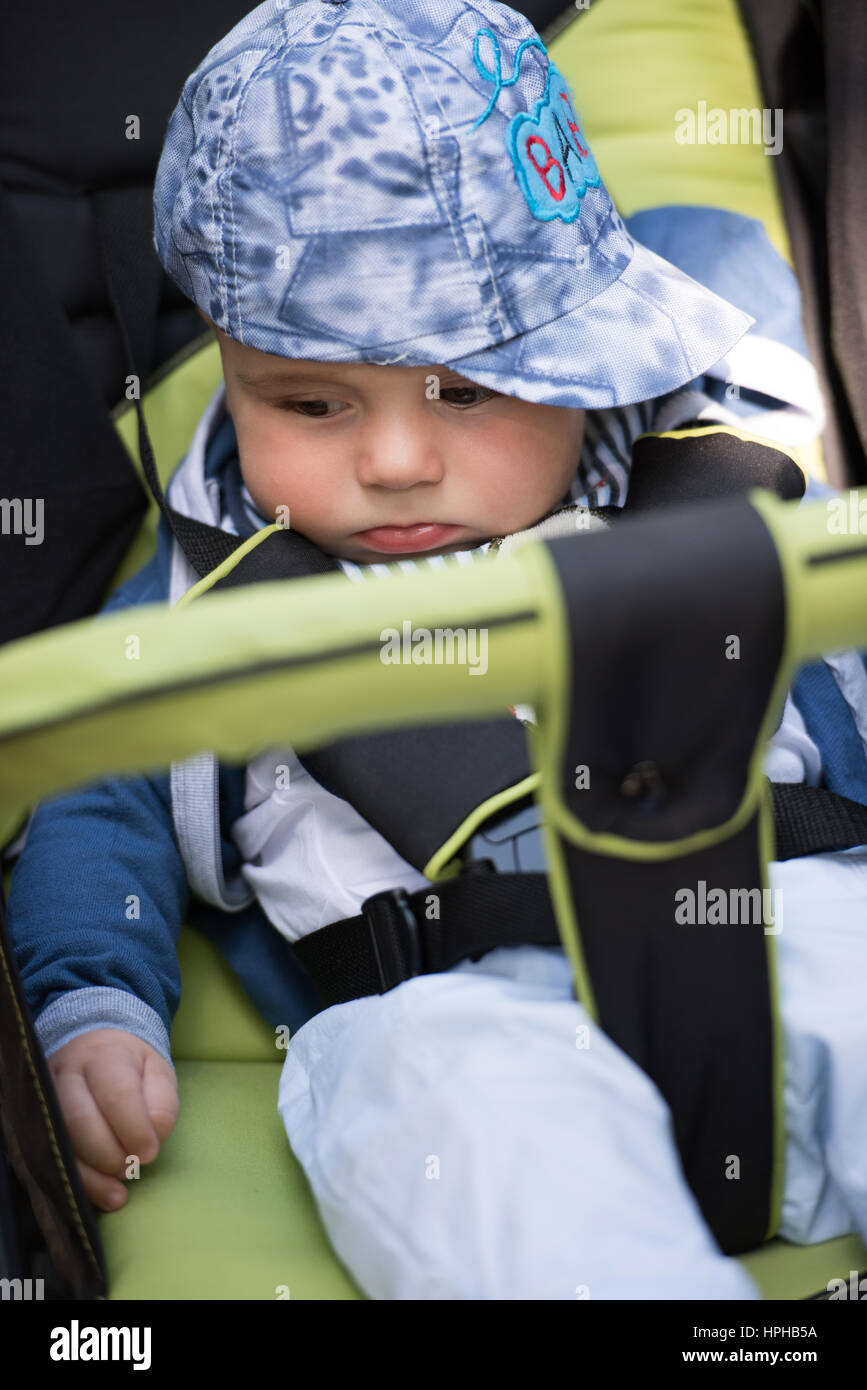little and very beautiful baby boy sitting in the pram and waiting for ...