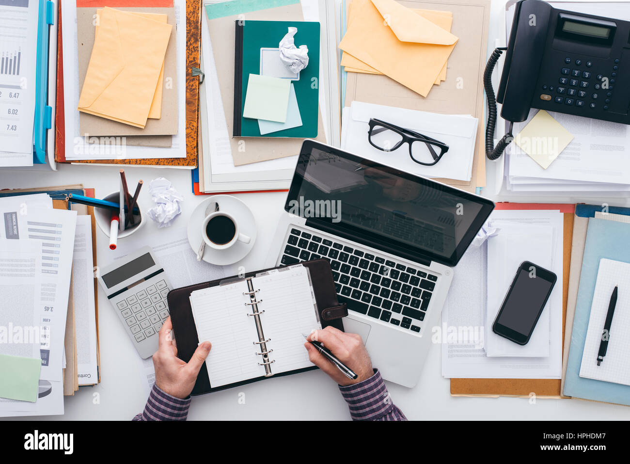 Businessman scheduling appointments on his organizer and full desktop ...