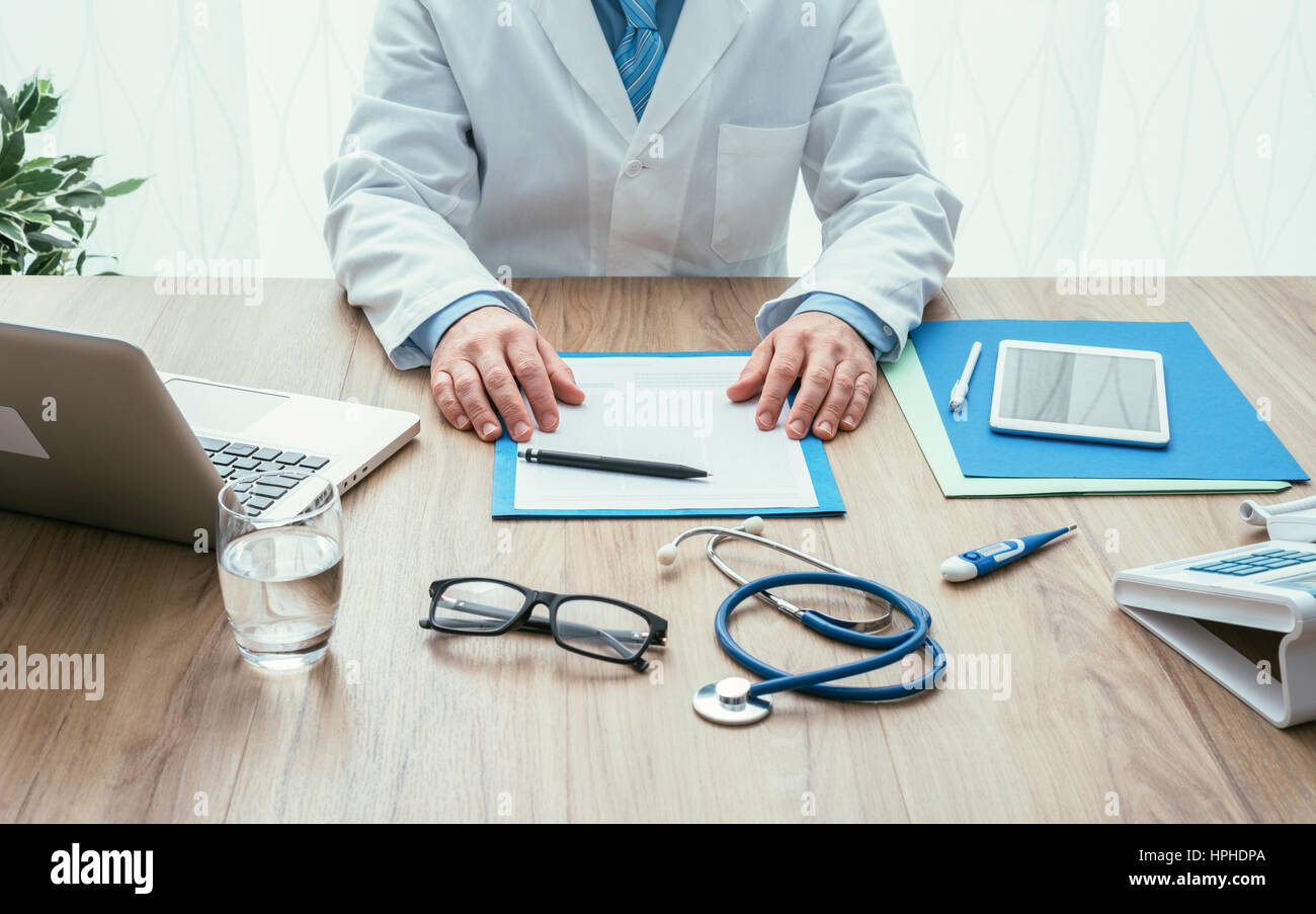 Professional doctor in his office working at desk, healthcare and ...