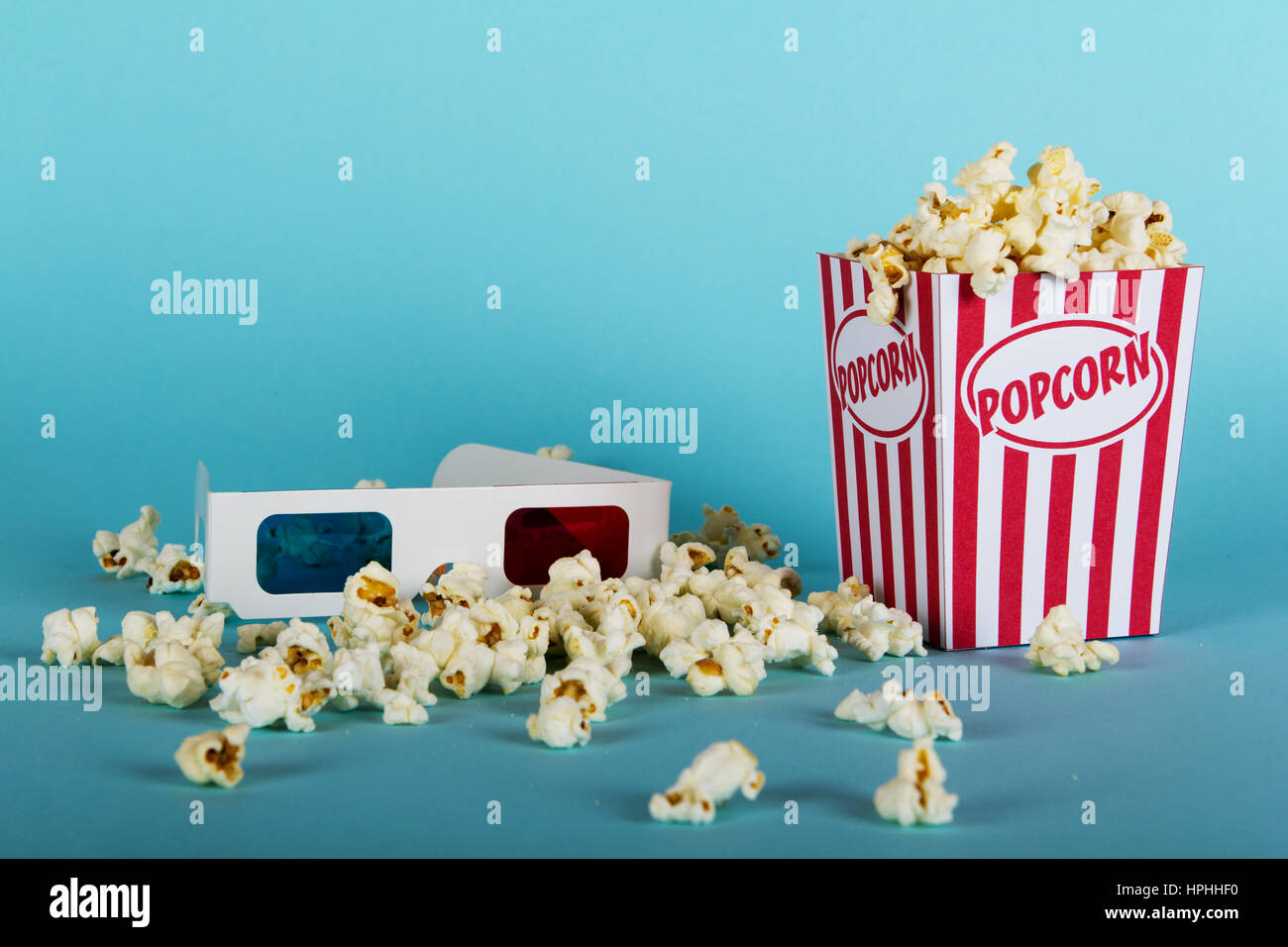 Bucket of popcorn against a blue background Stock Photo - Alamy