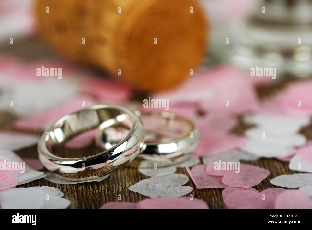 pair of white gold wedding rings on a wooden background with confetti ...