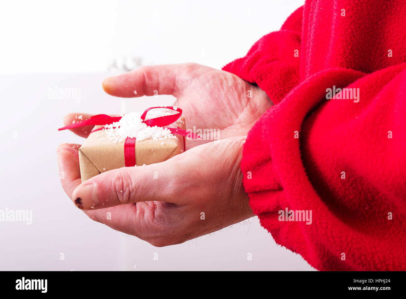 Open hands holding a present wrapped in a red ribbon Stock Photo - Alamy