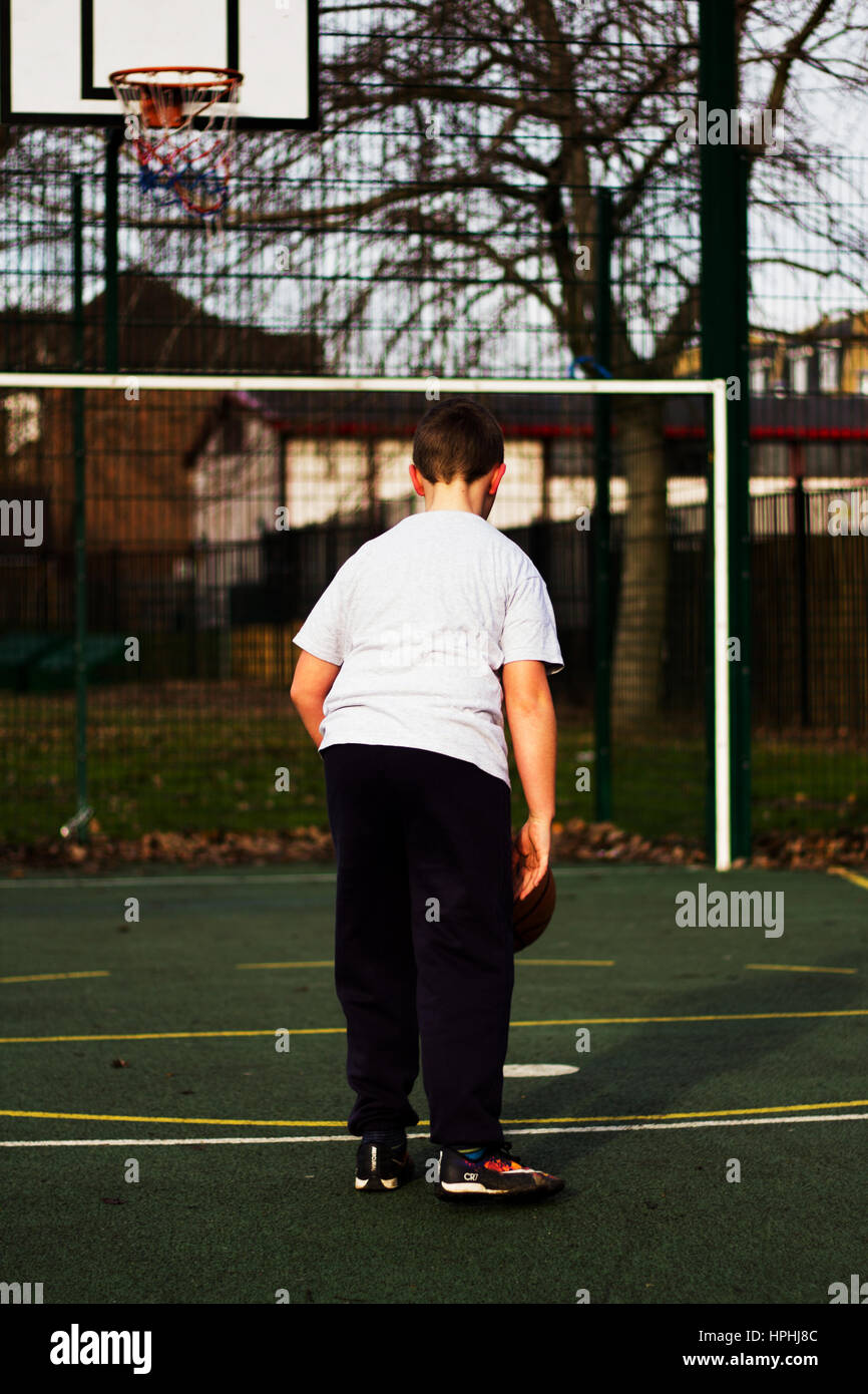 Child practicing playing basketball in a local park Stock Photo - Alamy