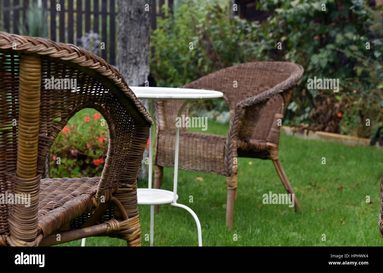 Rattan chairs and white table in a garden. Smoking area Stock Photo - Alamy