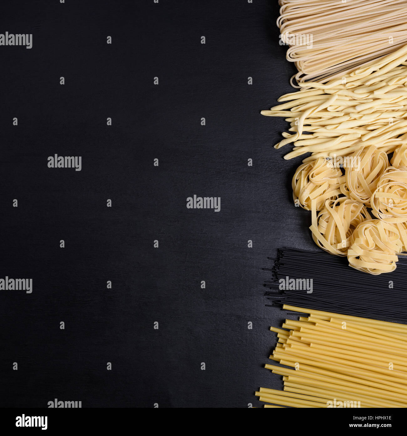 Variety of Italian dry pasta on a black background. Top view, copy ...