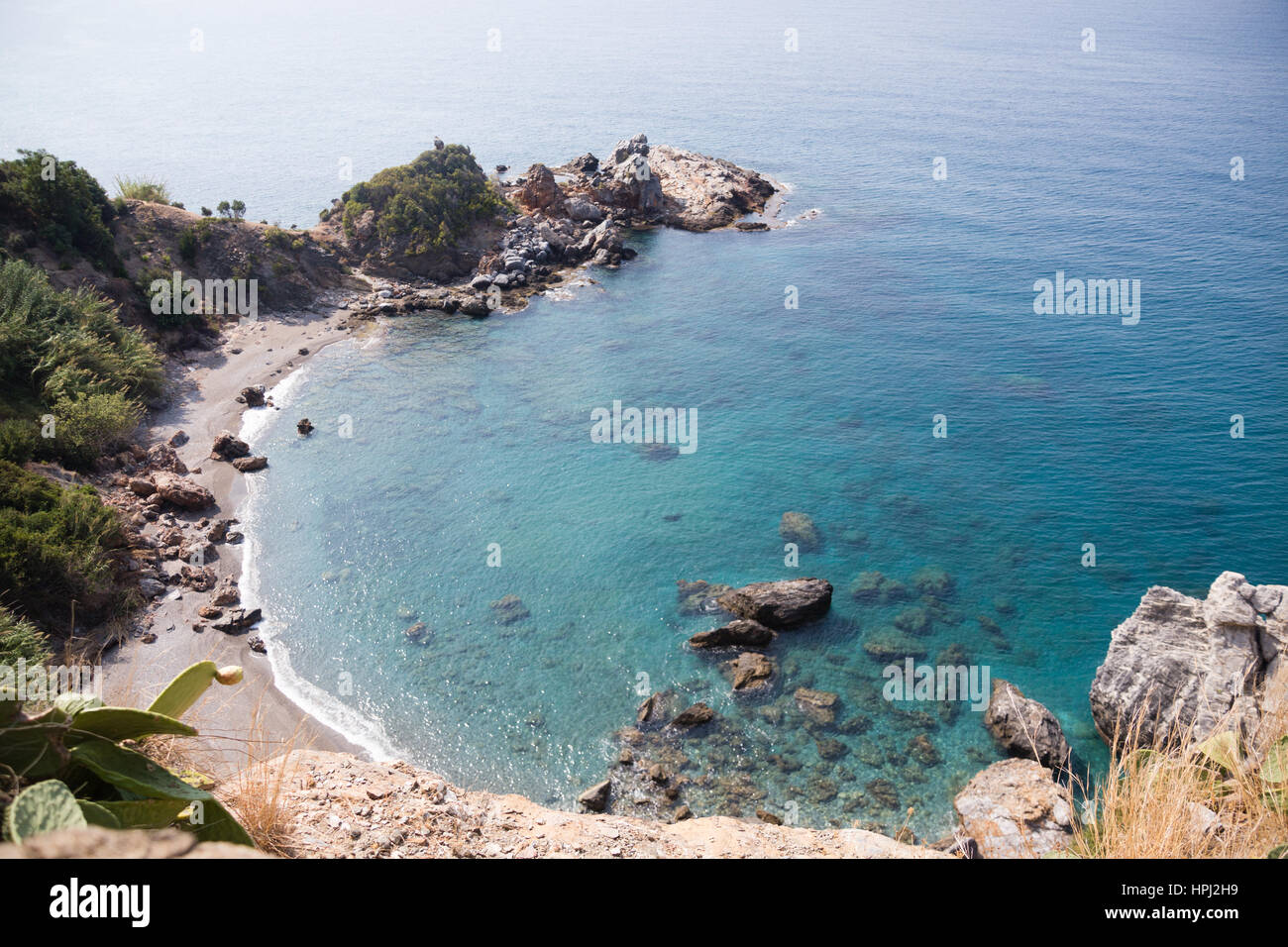 Round shaped sea bay surrounded by hills with turqoise sea and stones ...