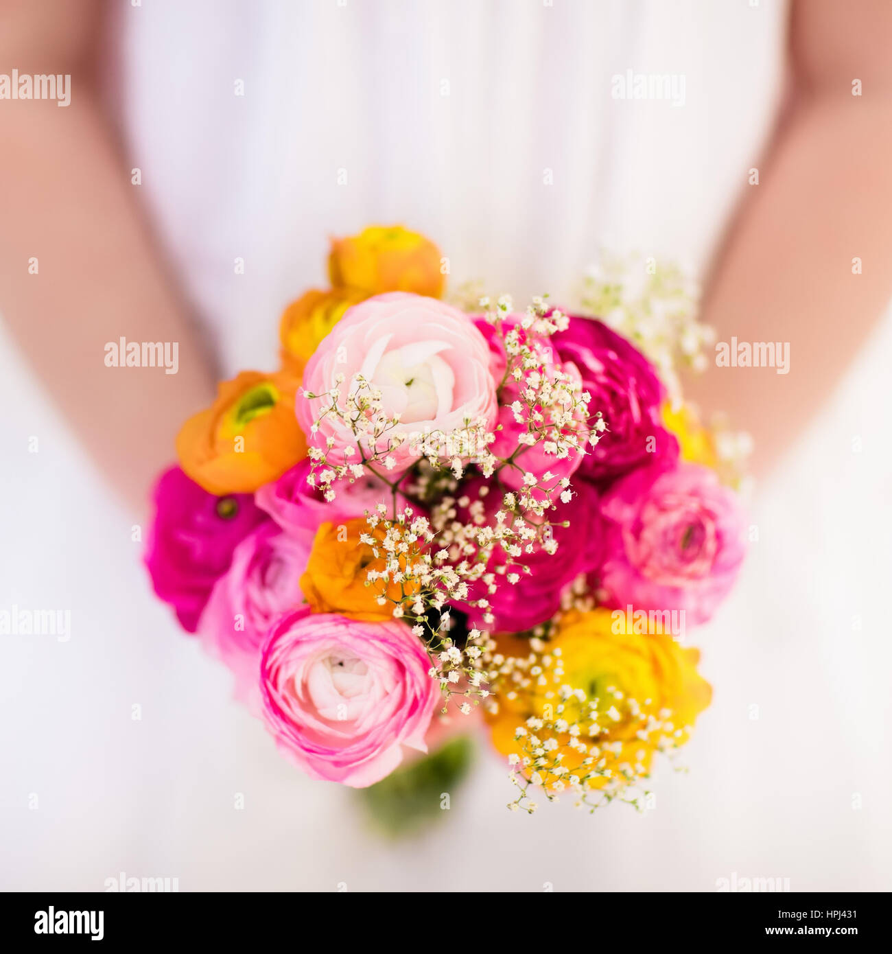 Cute little girl in white dress holding ranunculus flowers bouquet on ...