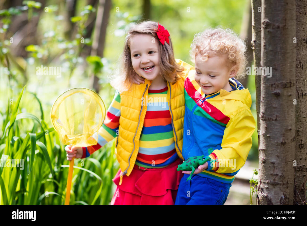 Children playing outdoors. Preschool kids catching frog with net. Boy ...