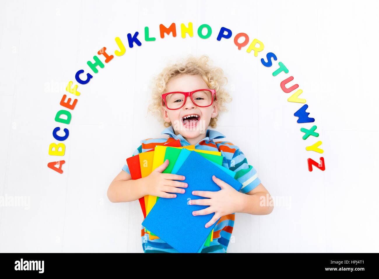 Happy preschool child learning to read and write playing with colorful ...