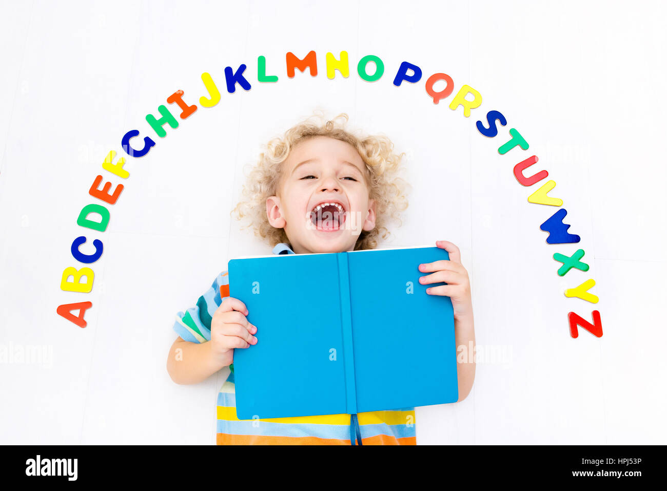 Happy preschool child learning to read and write playing with colorful ...