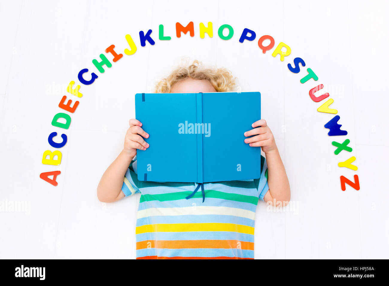Happy preschool child learning to read and write playing with colorful ...