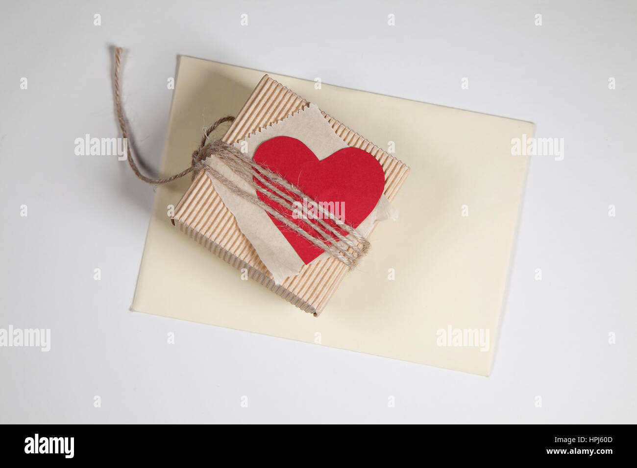 A box with a red paper heart, wrapped a rope lying on the envelope on a ...