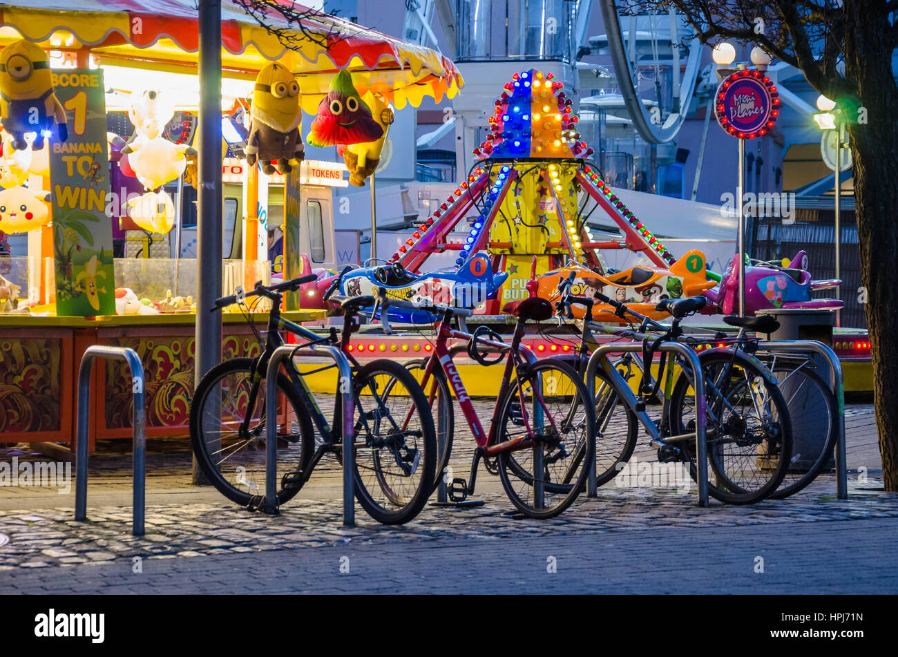 Bicycles left at a bike rack in front of a fairground ride and stall in ...
