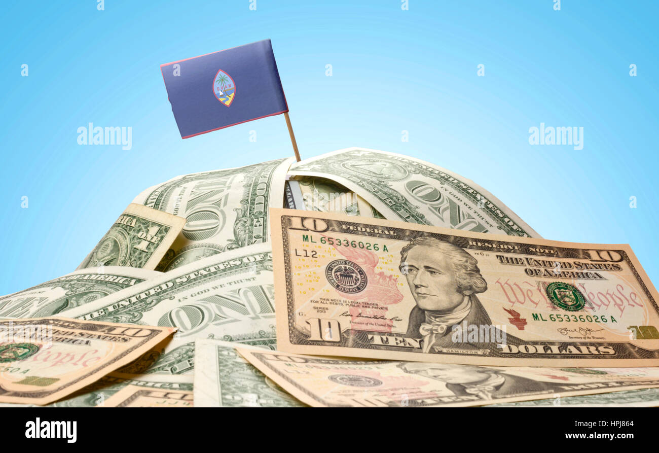 The national flag of Guam sticking in a pile of american dollars ...