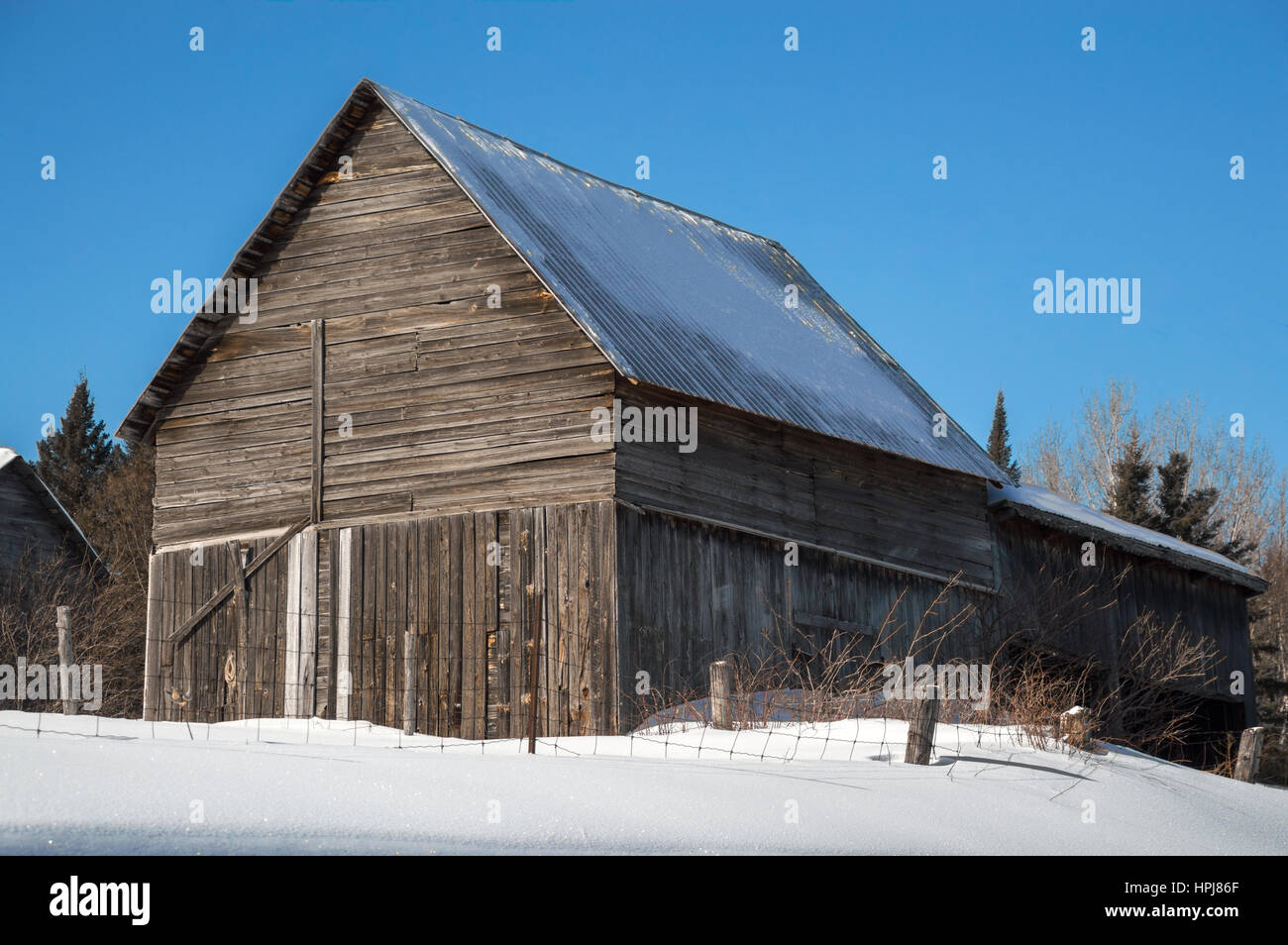 A snow covered barns in the sunshine in Northern Ontario. Blue sky and ...