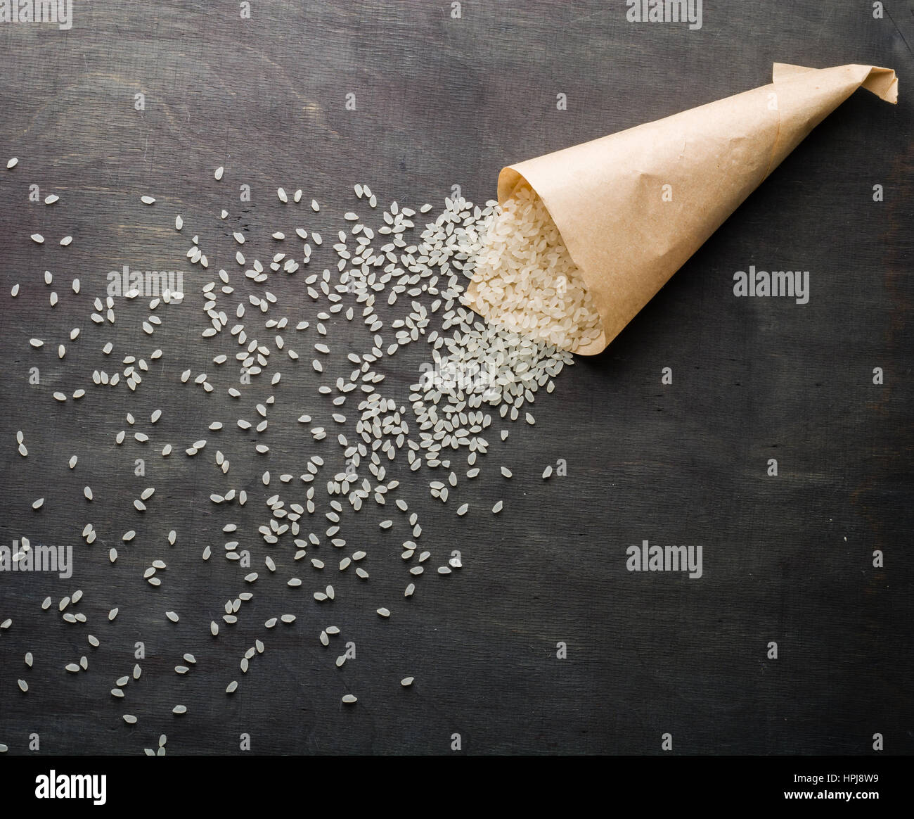 White rice scattered over the dark wooden table of a paper bag. View ...