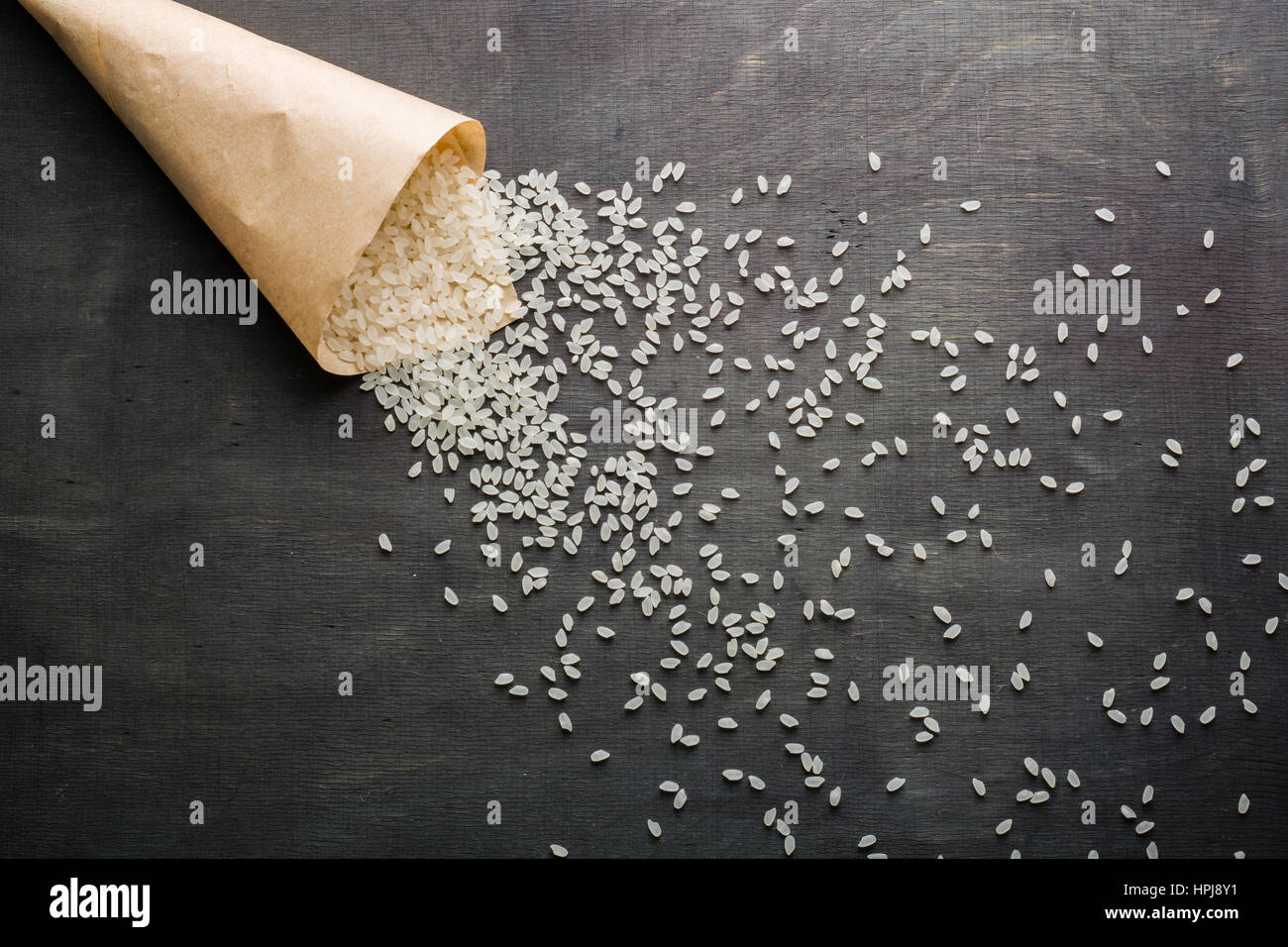White rice scattered over the dark wooden table of a paper bag. View ...